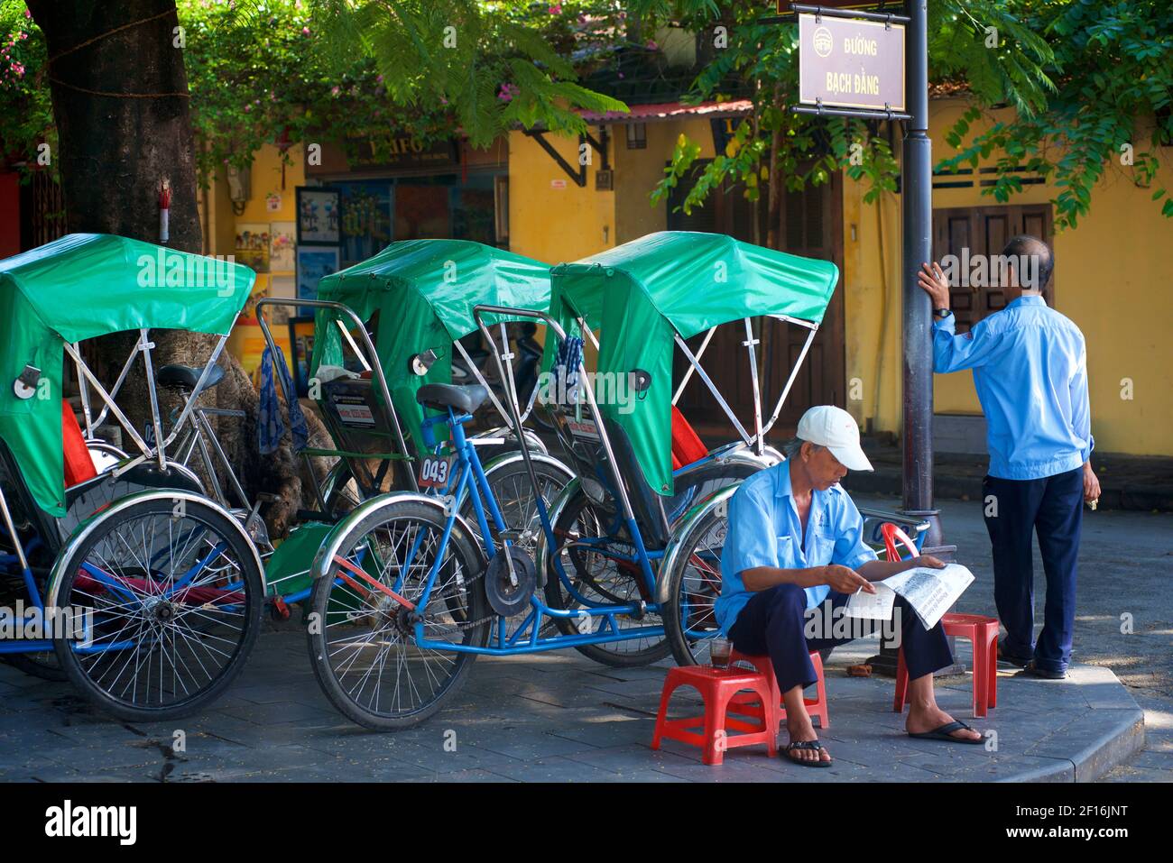 Vietnamese rickshaw drivers with their cycles, waiing for business. Hoi ...