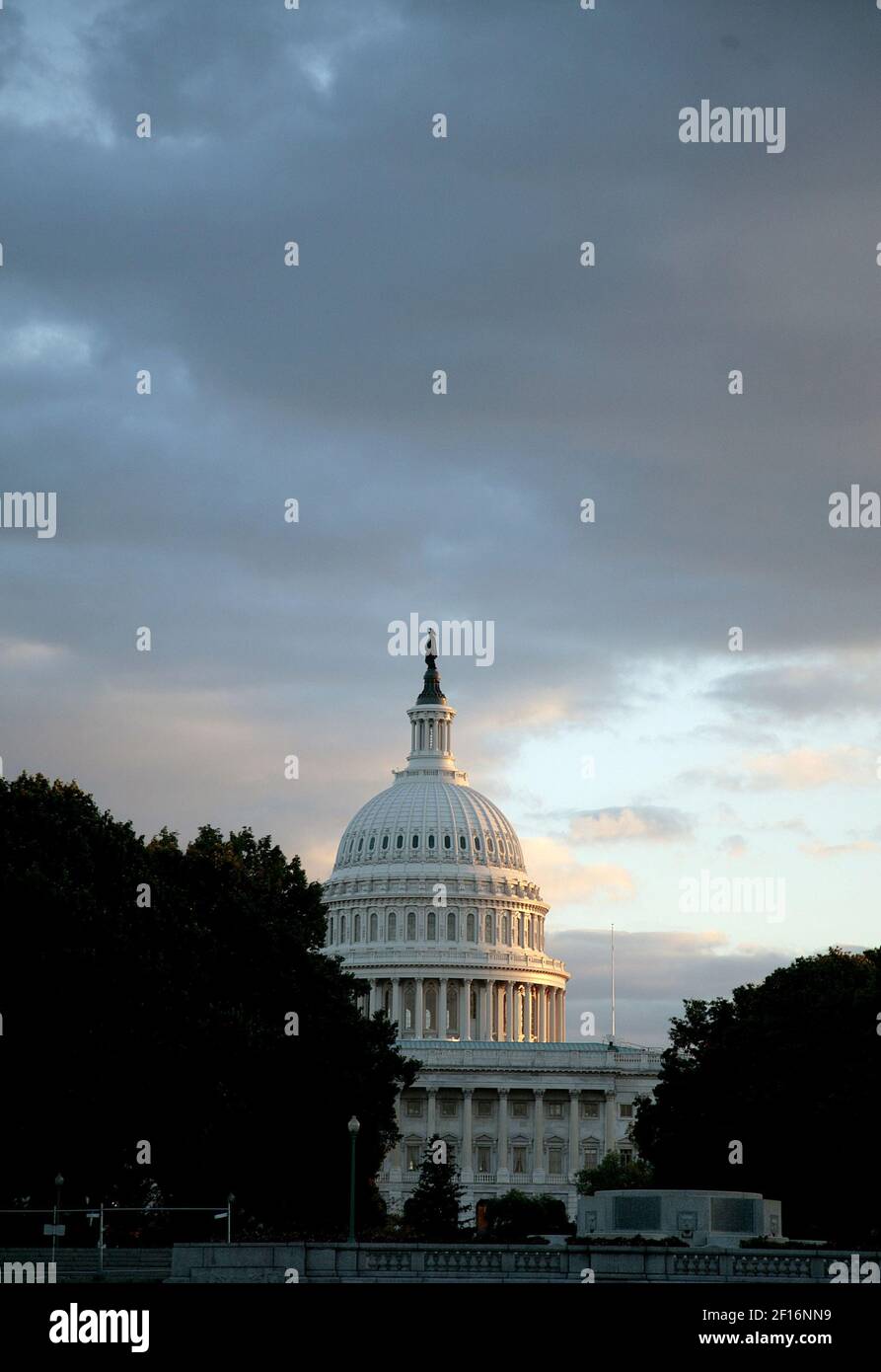The setting sun casts an orange glow on the U.S. Capitol Building in ...