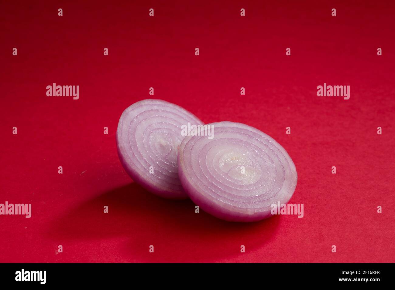 Onion slices, arranged beautifully on a red textured background ...