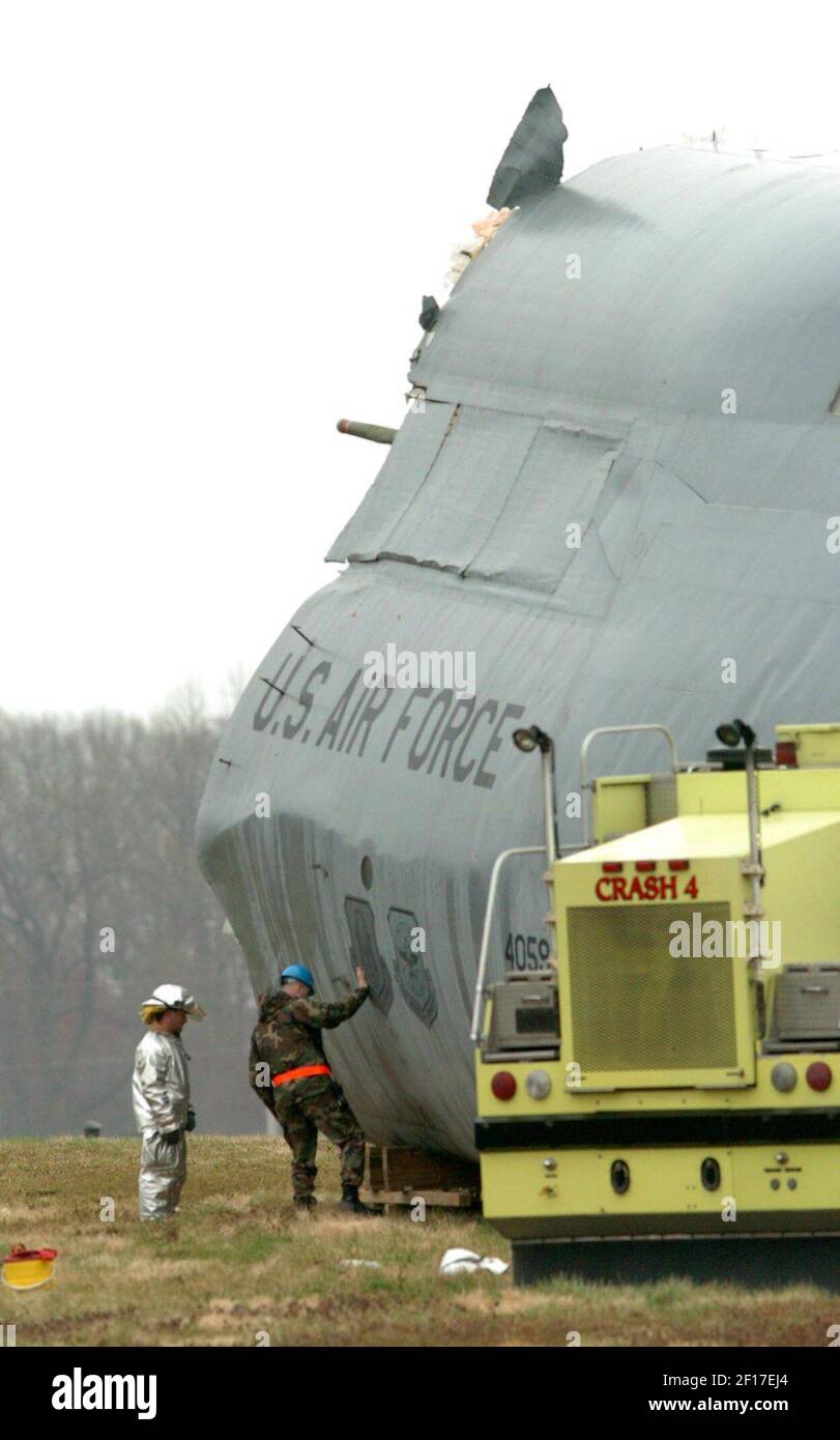 Military emergency response personnel inspect the nose section of a C-5 ...