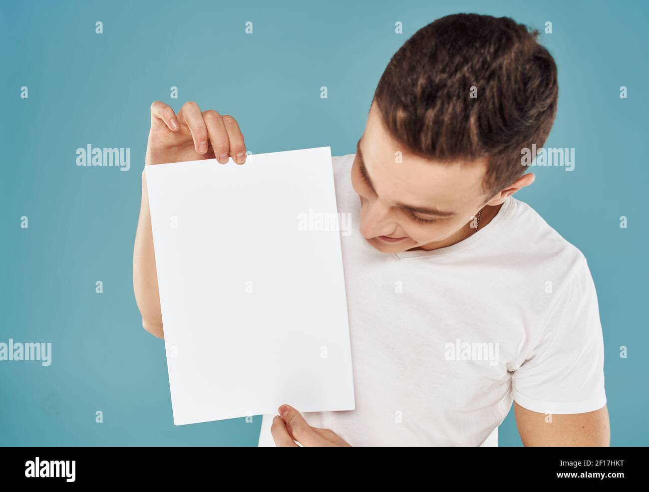 Man with white sheet of paper poster blue background mockup Stock Photo ...