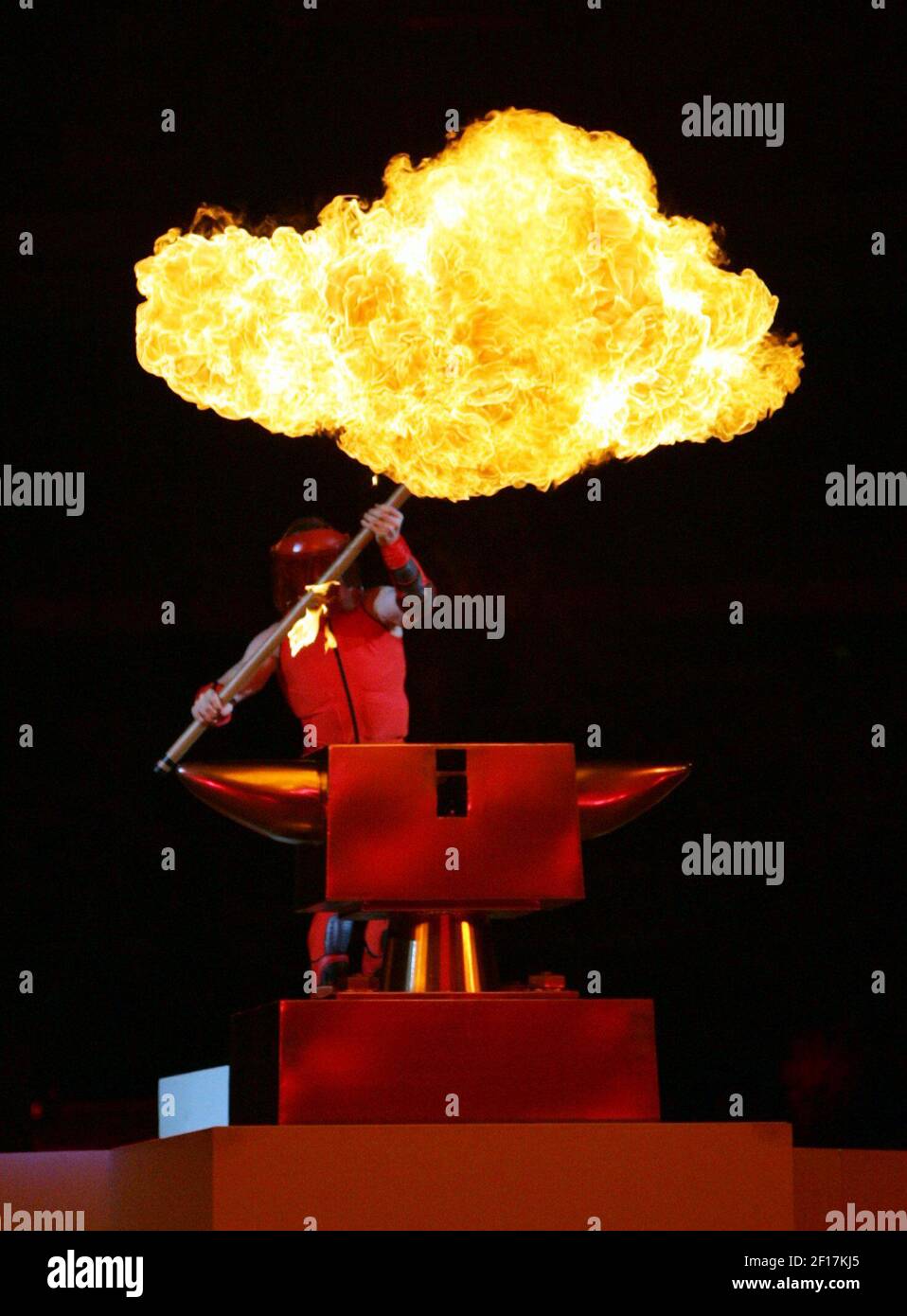 A performer uses a hammer to hit an anvil as flames erupt during ...
