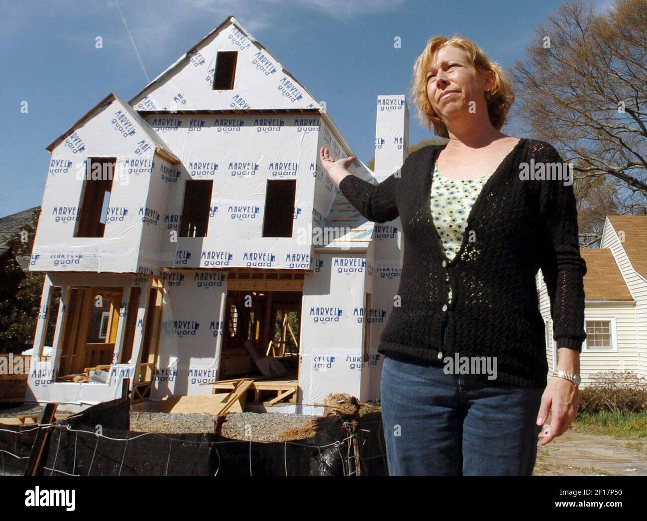Activist Liz Coyle stands in between a large house under construction ...