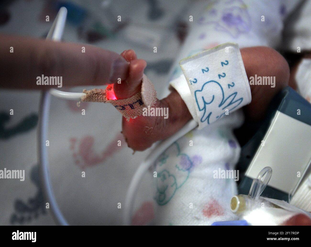 Athena Bolton, left, touches the tiny toe of her daughter Adelaide ...