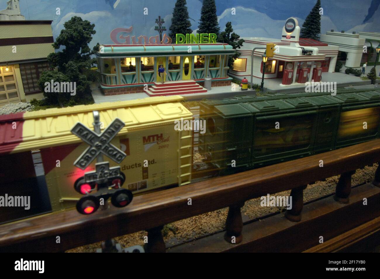 A miniature train speeds throough a crossing in a town scene on tracks ...