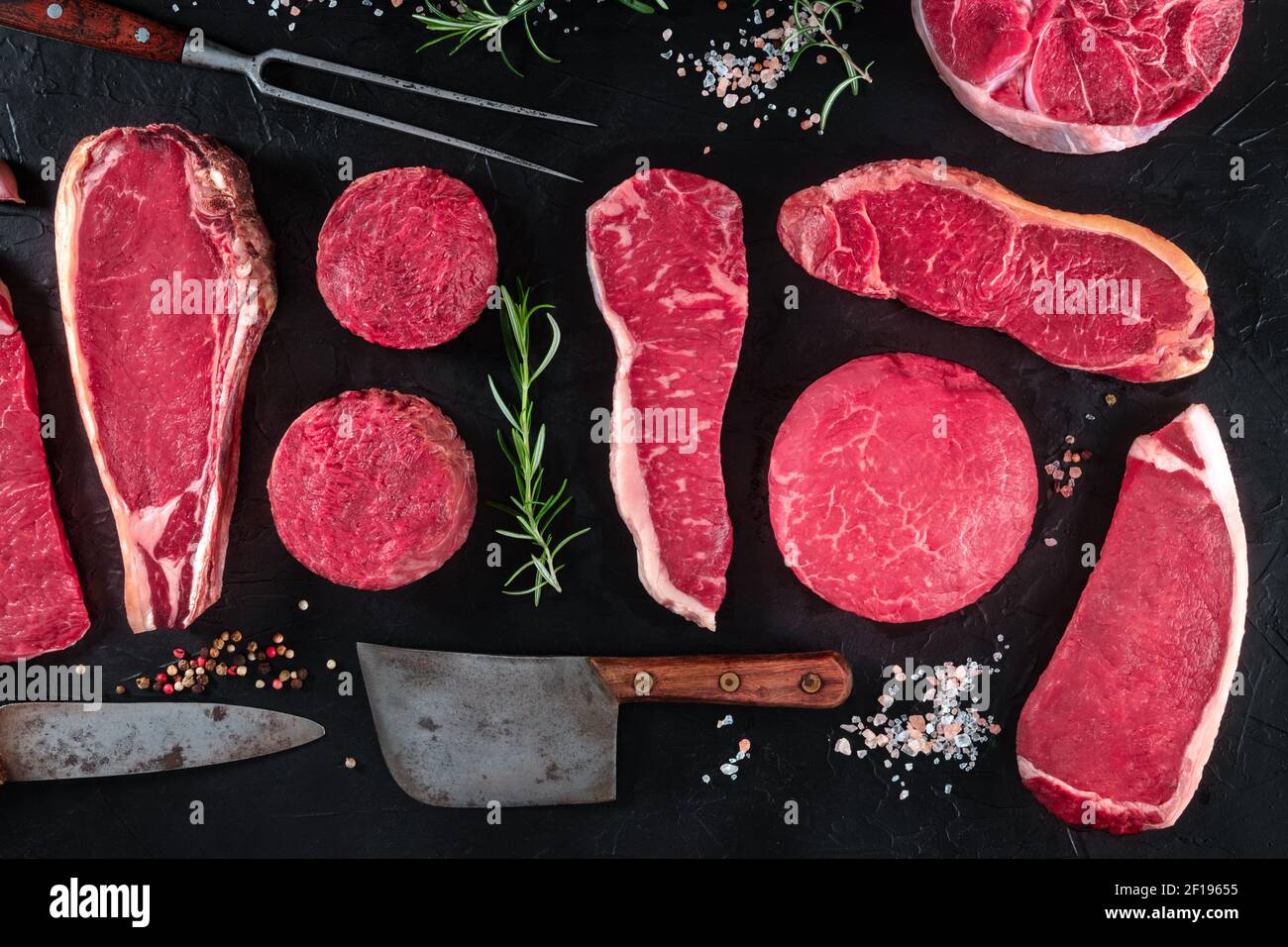 Raw meat, different cuts of beef, overhead flat lay shot with knives on ...