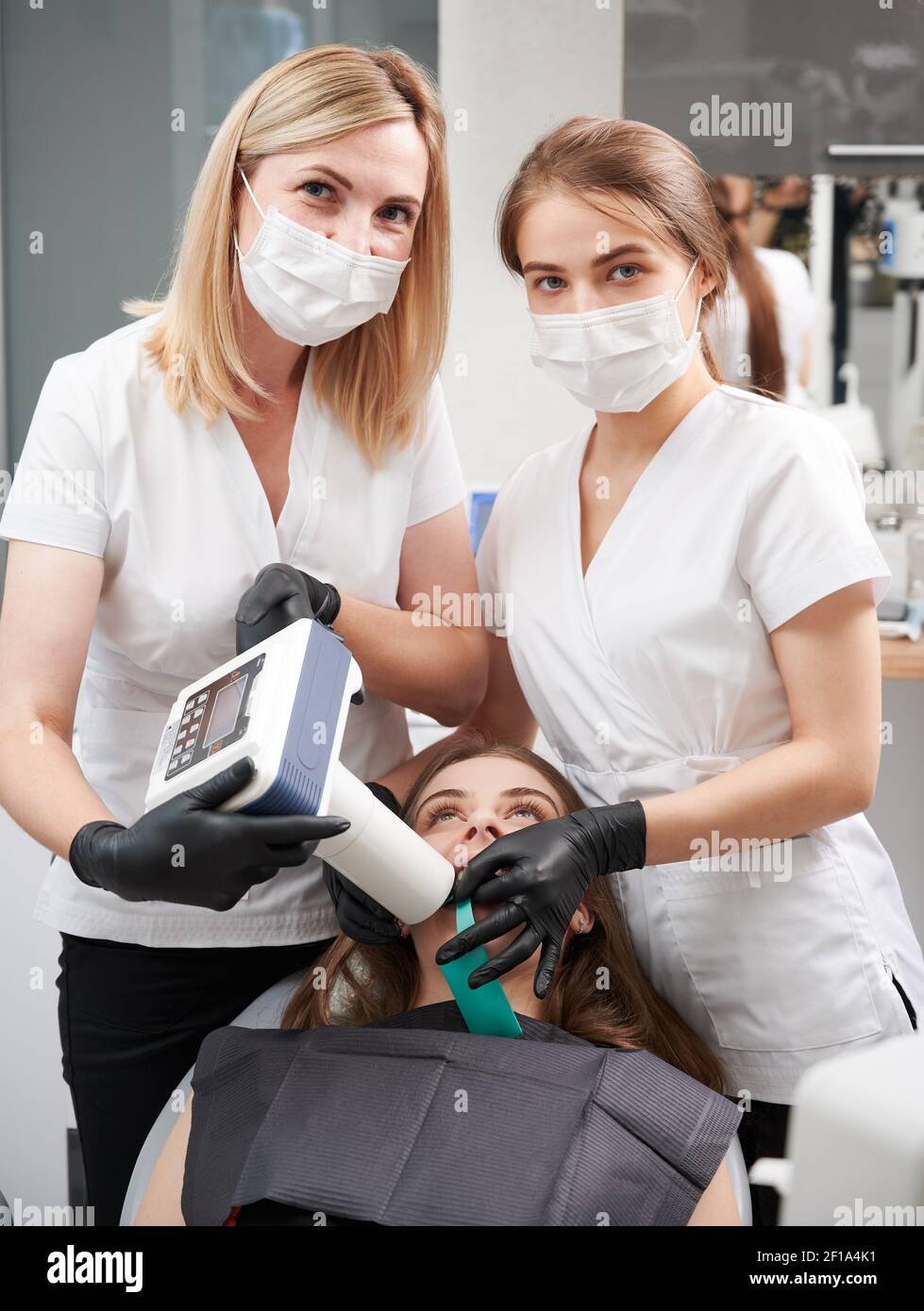 Doctors using portable dental x-ray machine while examining female ...