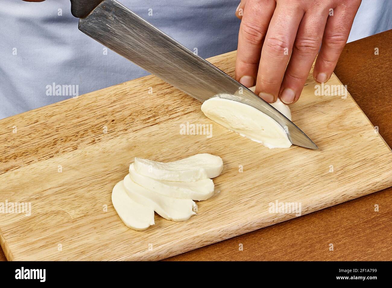 The process of cutting the cheese mozzarella on a cutting board closeup ...