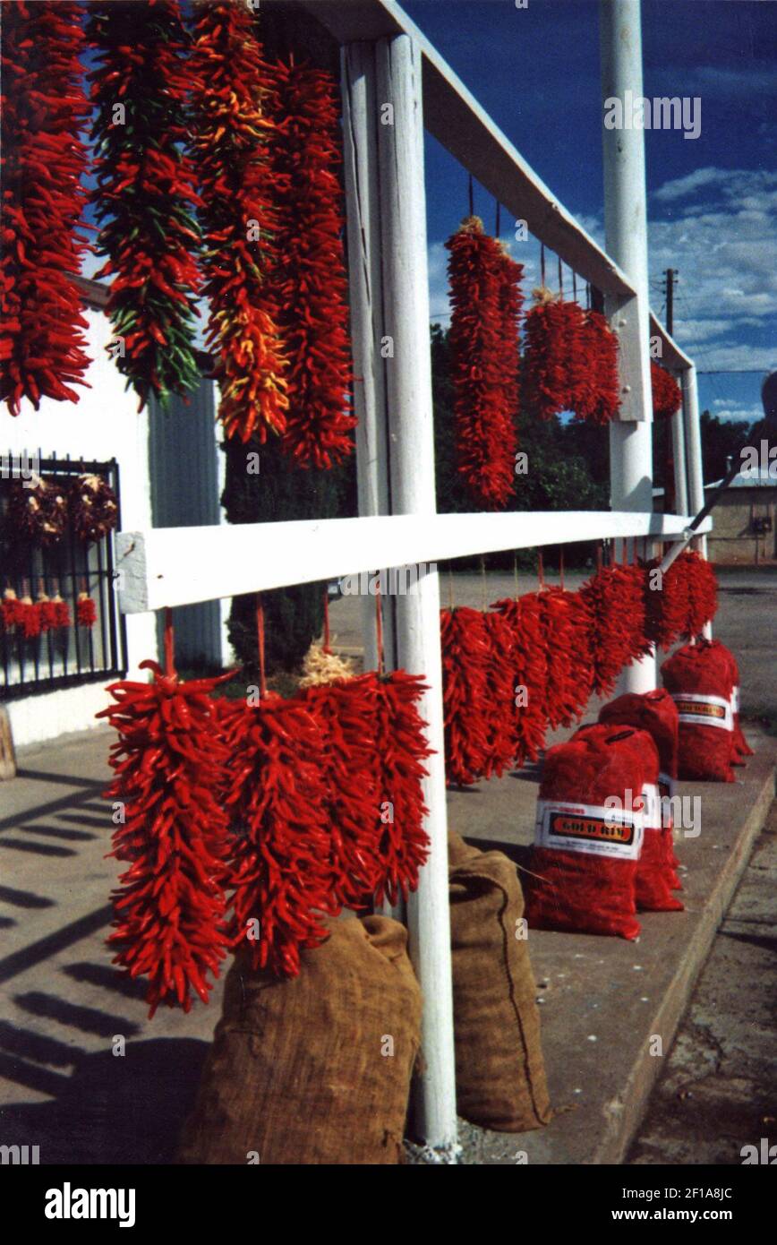 Red chile ristras and sacks of green chiles at a roadside stand in New ...