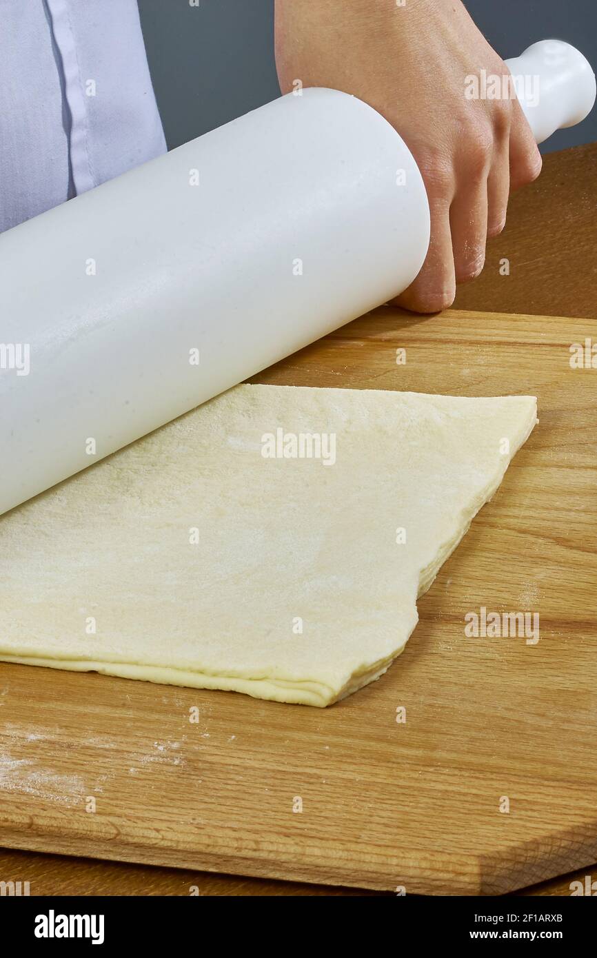 Roll out the dough Closeup hand of chef baker in uniform blue apron ...