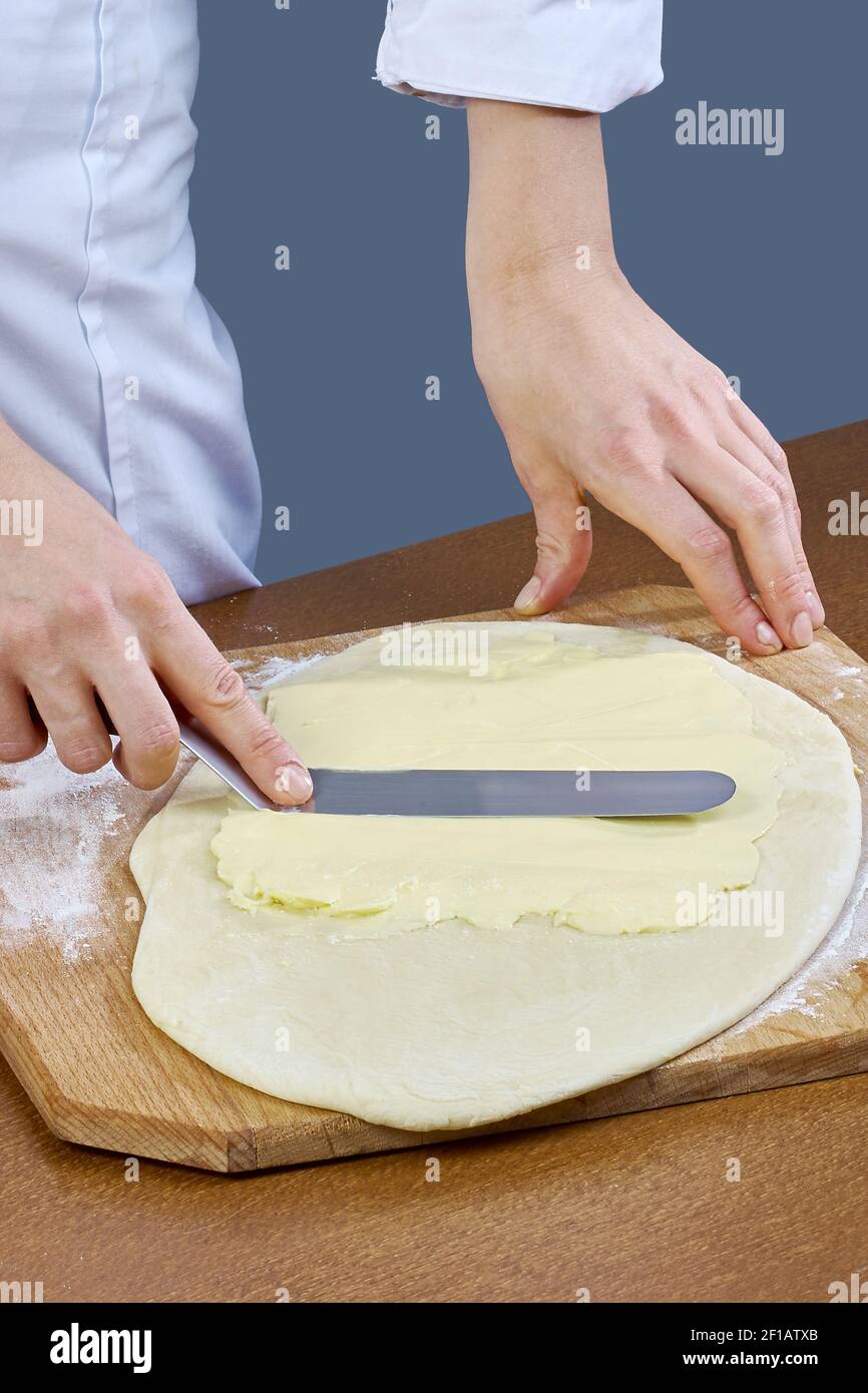 Chef smears butter on the dough for the preparation of baking cooking ...