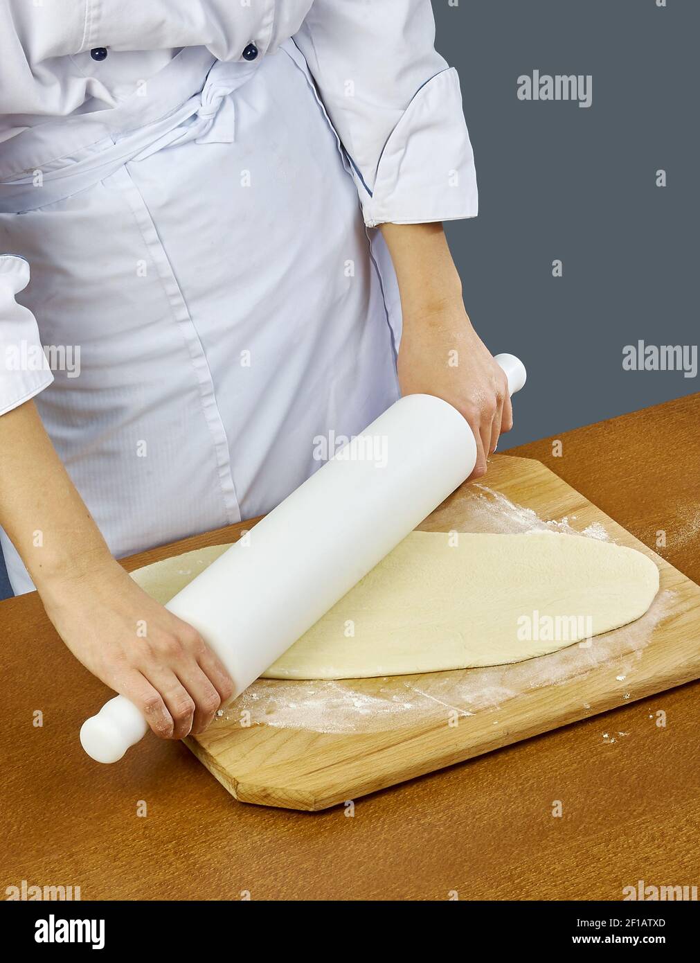 Roll out the dough Closeup hand of chef baker in uniform blue apron ...