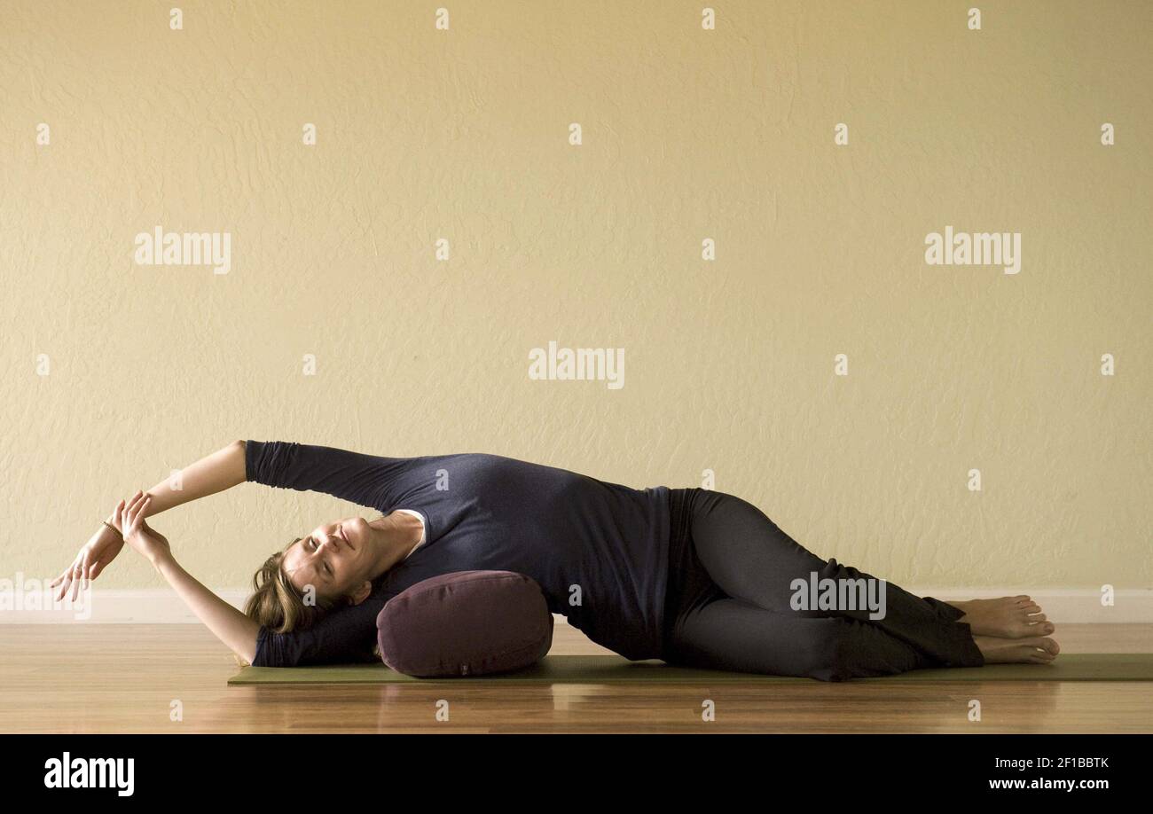 Kim Wagaman demonstrates a side stretch with a bolster at Yoga Solution ...