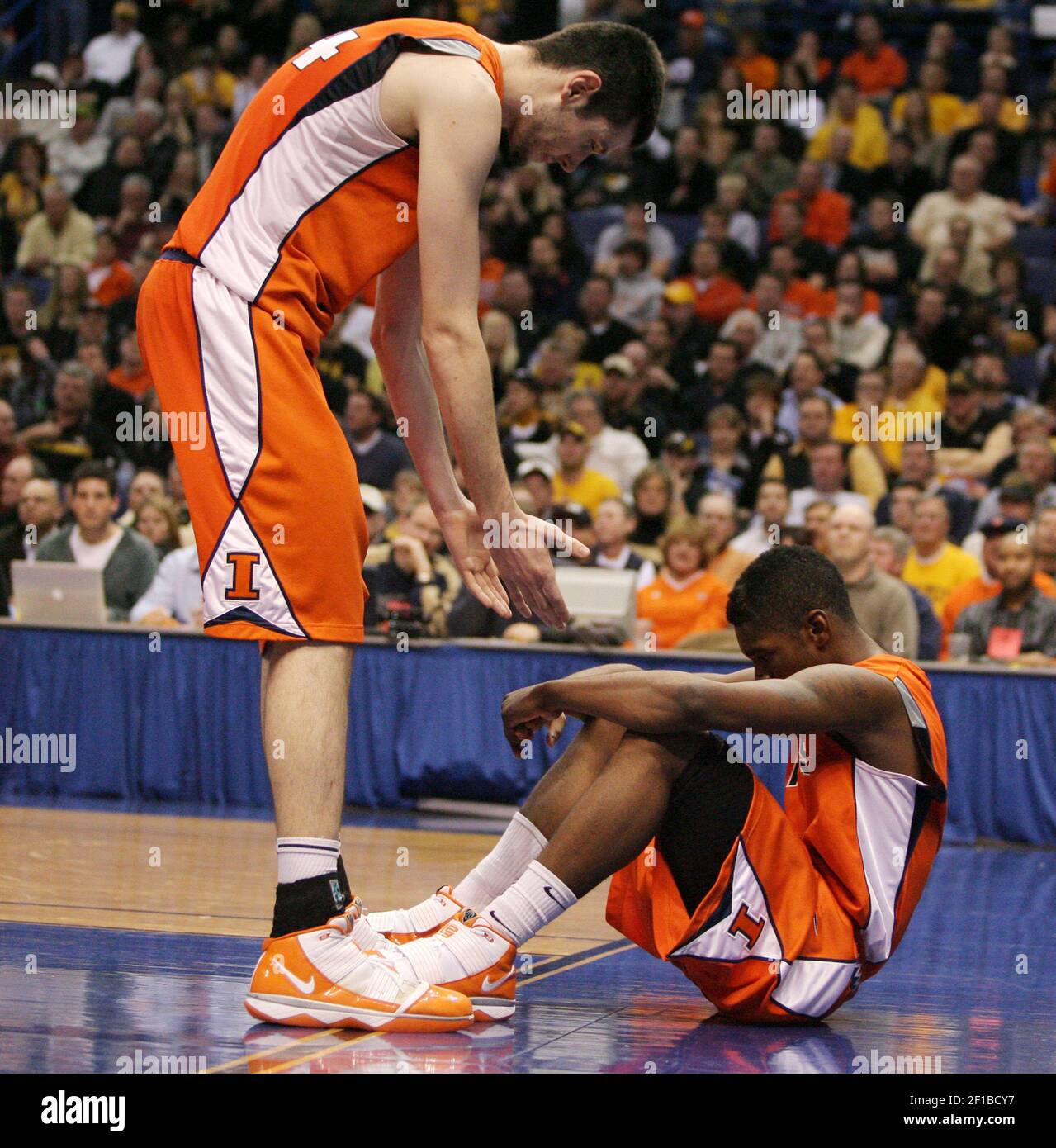 Illinois center Mike Tisdale (left) assists teammate Brandon Paul off ...