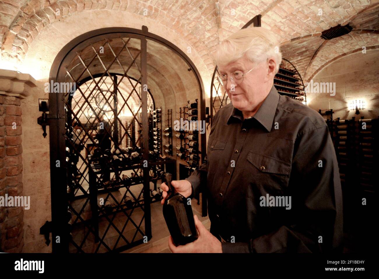 William Koch holds a bottle of wine in the wine cellar of his home on ...