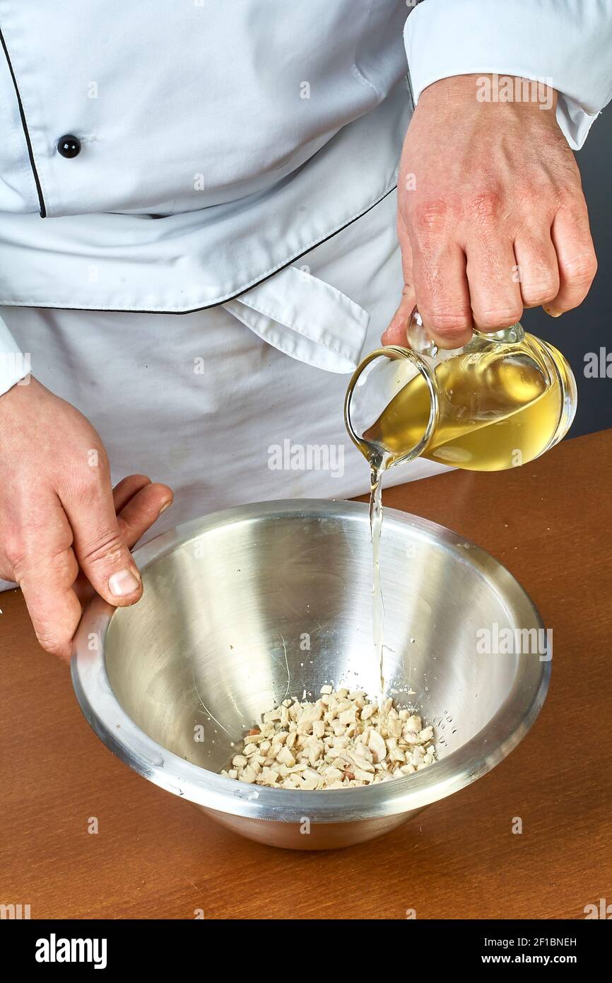 The cook pours olive oil into a bowl full of recipes for food Stock ...