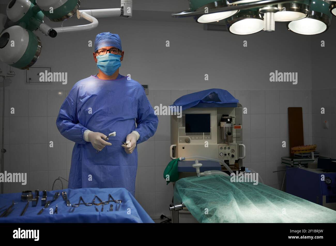 Front view of plastic surgeon holding medical instruments and looking ...