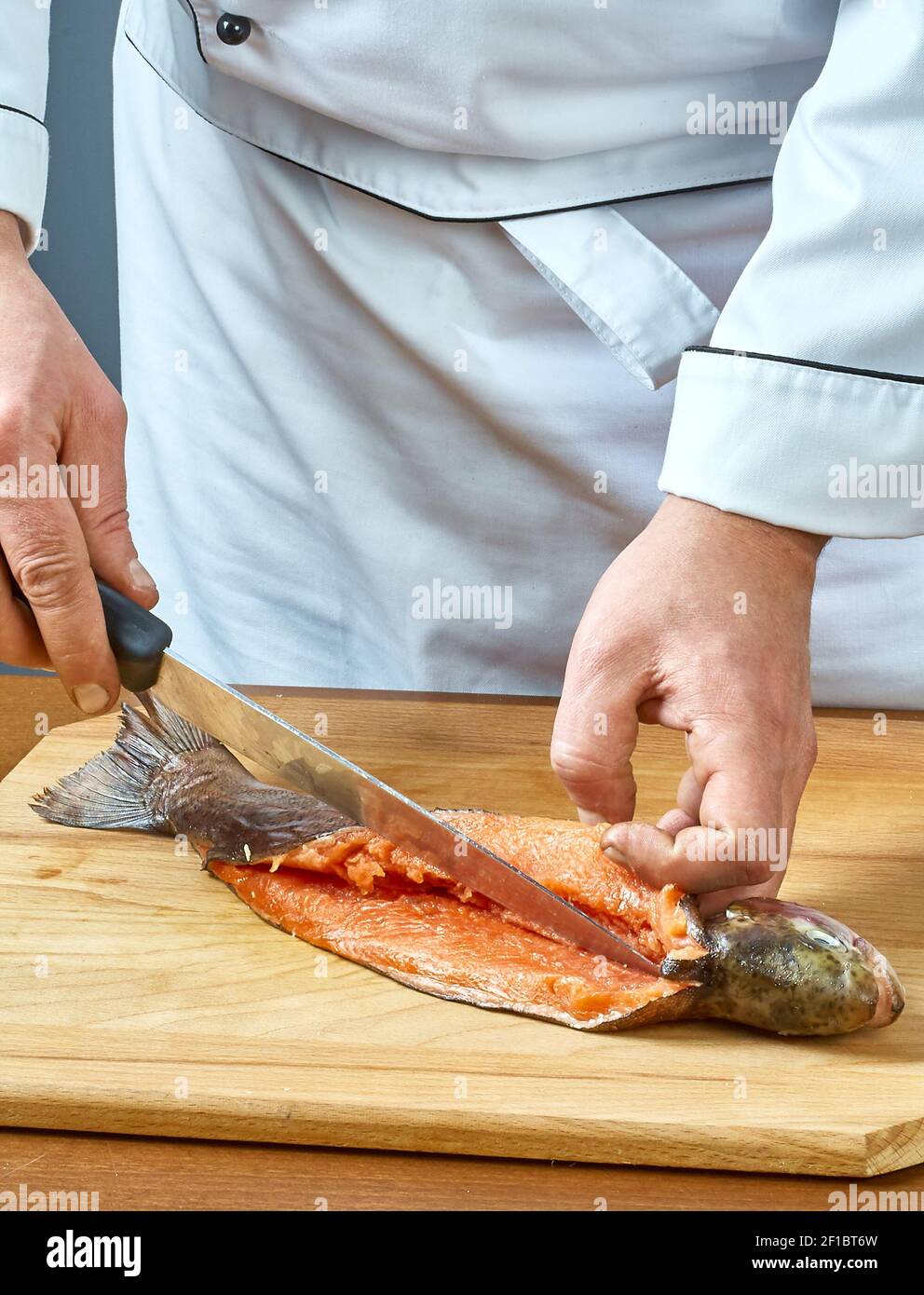 Cook cuts fish full collection of food recipes Stock Photo - Alamy