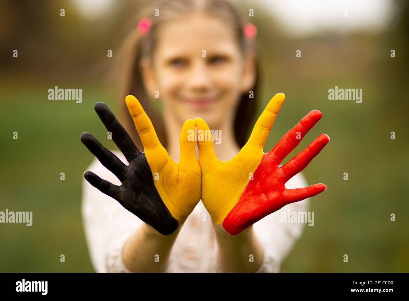 Child girl show hands painted in Belgium flag colors walking outdoor ...