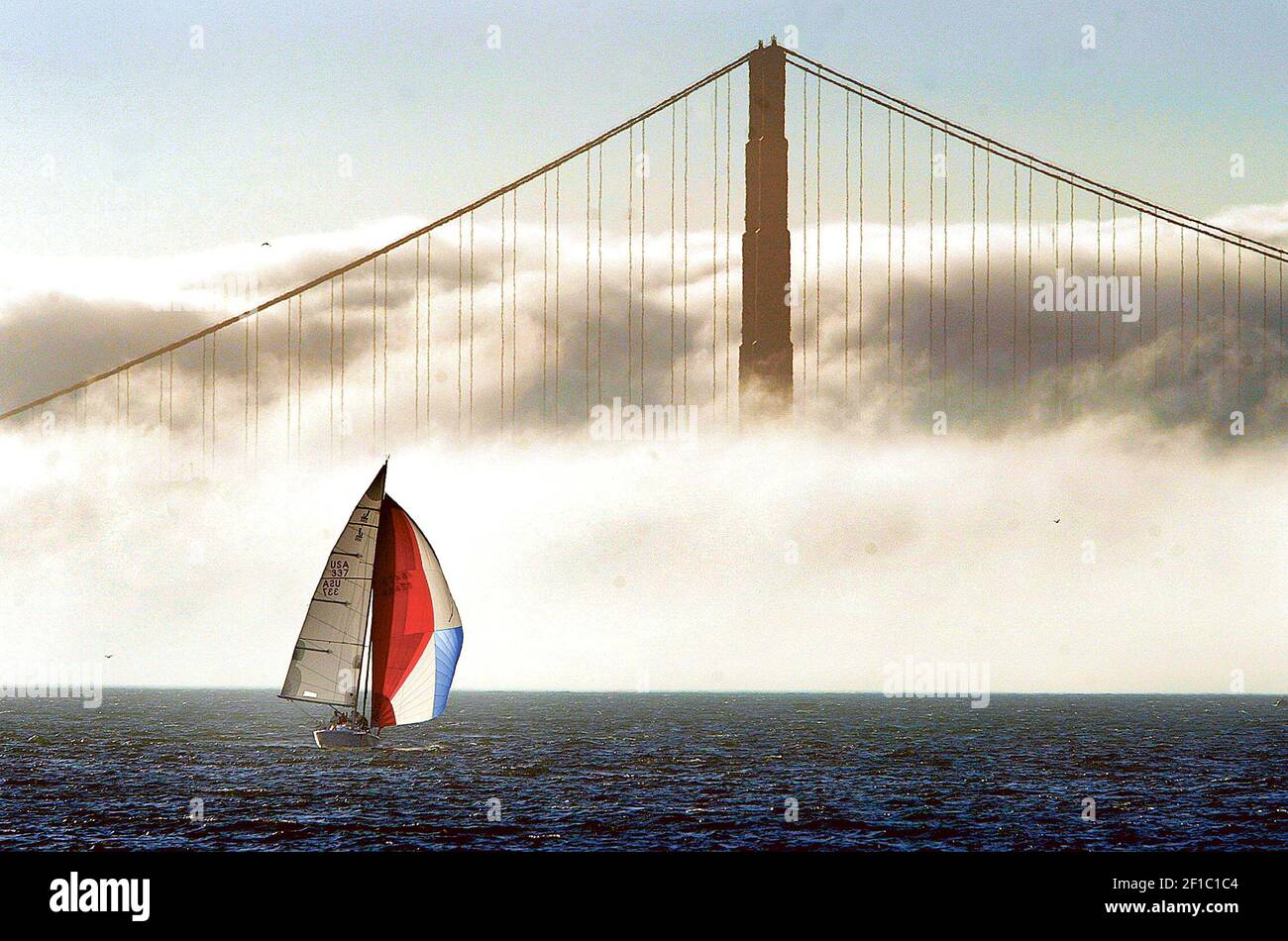 Fog bumps into the San Francisco Bay Bridge while the sun lights up the ...