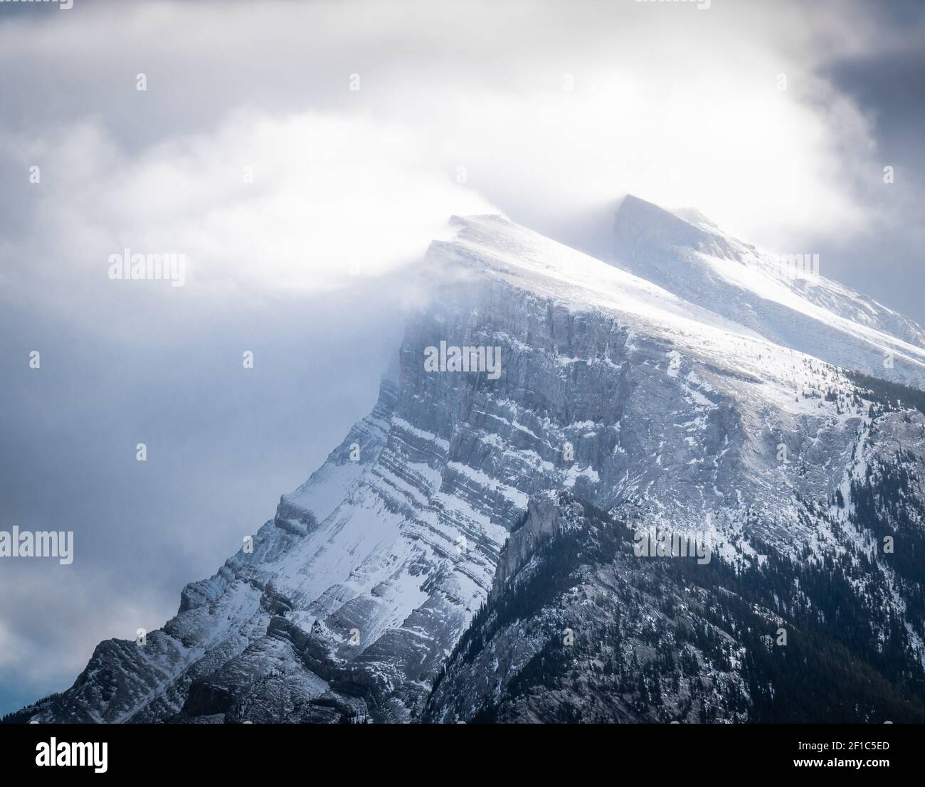 Snowy mountain peak (Mount Rundle) covered by snow and shrouded by ...