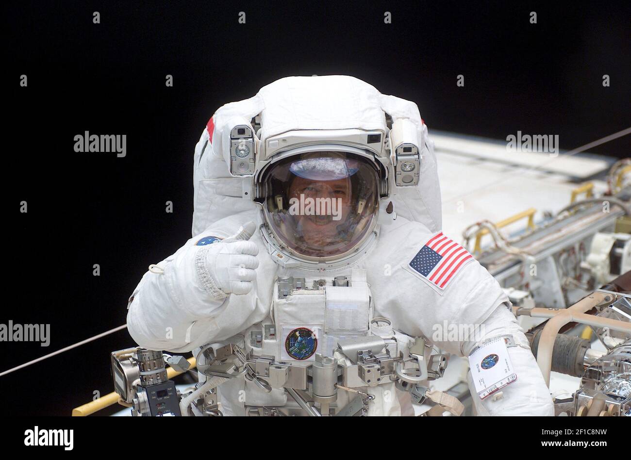 NASA Astronaut John Grunsfeld signals to a crew mate inside the cabin ...