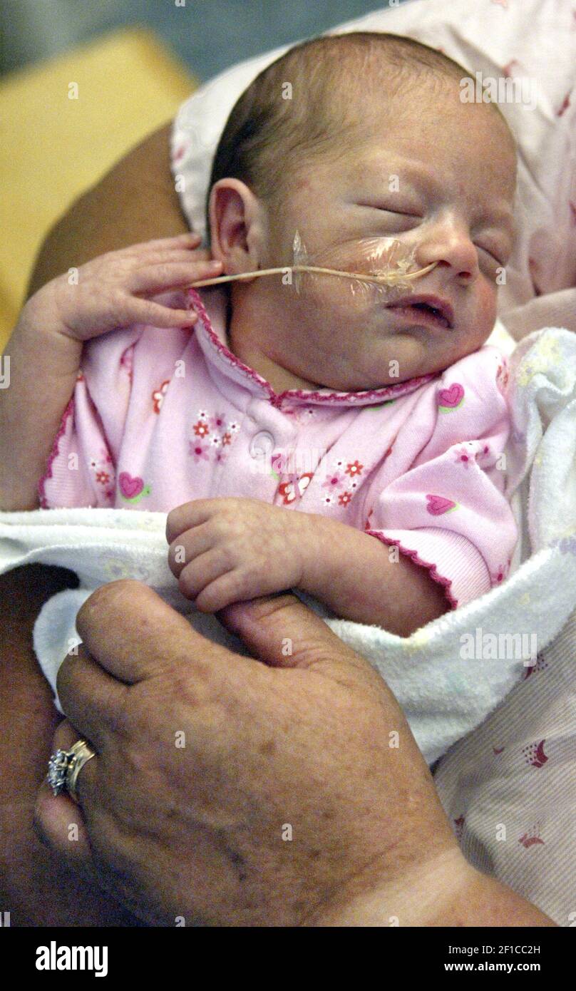 Taylor Fossum grips volunteer Kathy VanDenBergh's thumb while sleeping ...