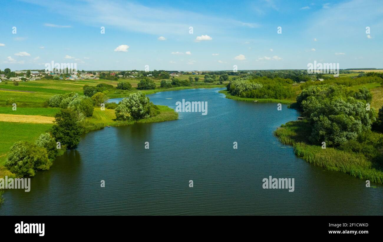 Aerial view of the river surrounded by green fields through which the ...