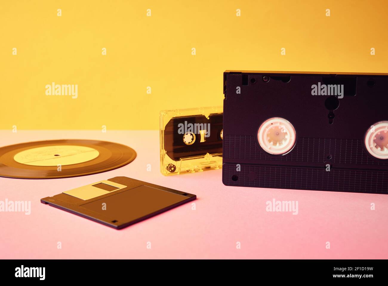 Vinyl disc, floppy diskette, vhs and tape cassete on yellow background ...