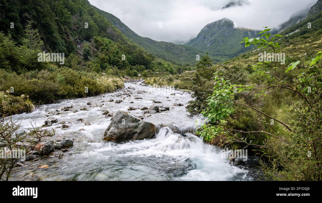 River flowing through the valley, surrounded by mountains shrouded in ...