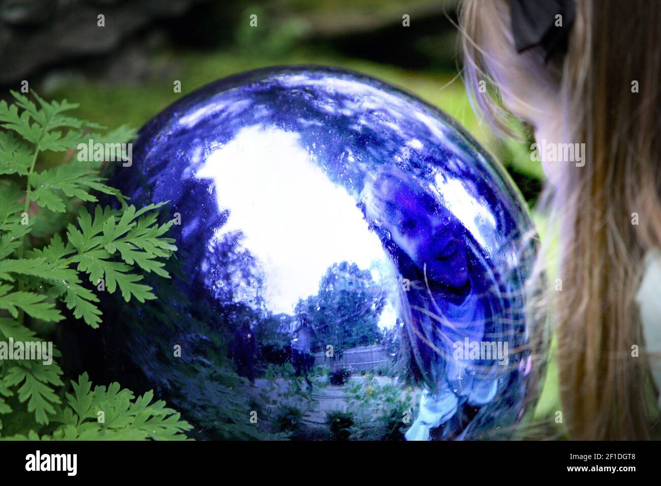 Natalie Bauder views her play realm through the gazing ball as she ...