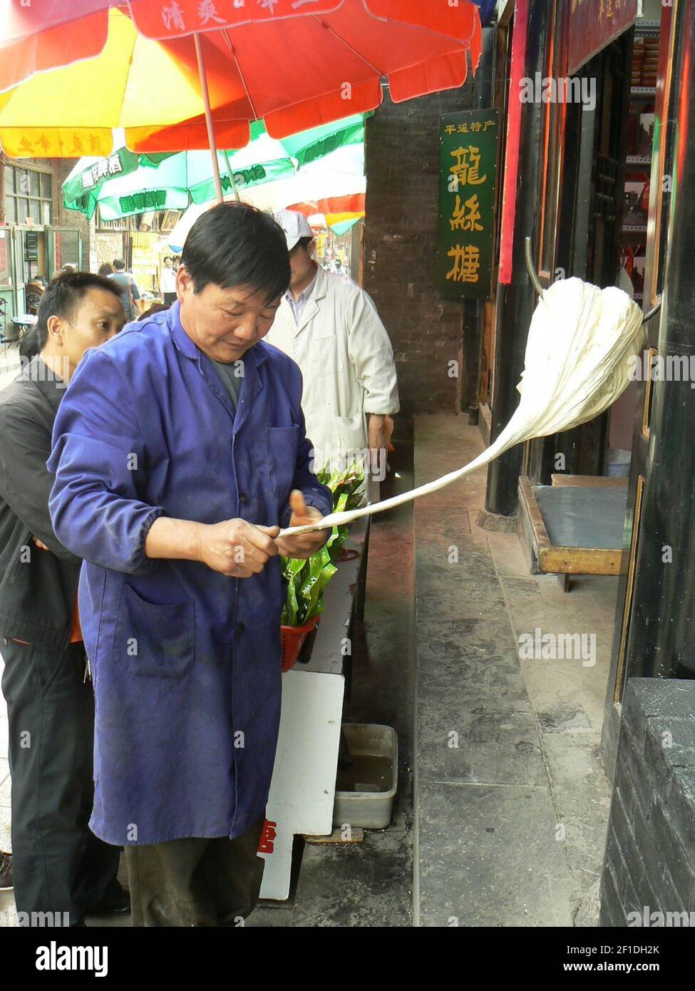 A street vendor makes ginger candy in Pingyao, China. He stretches the ...