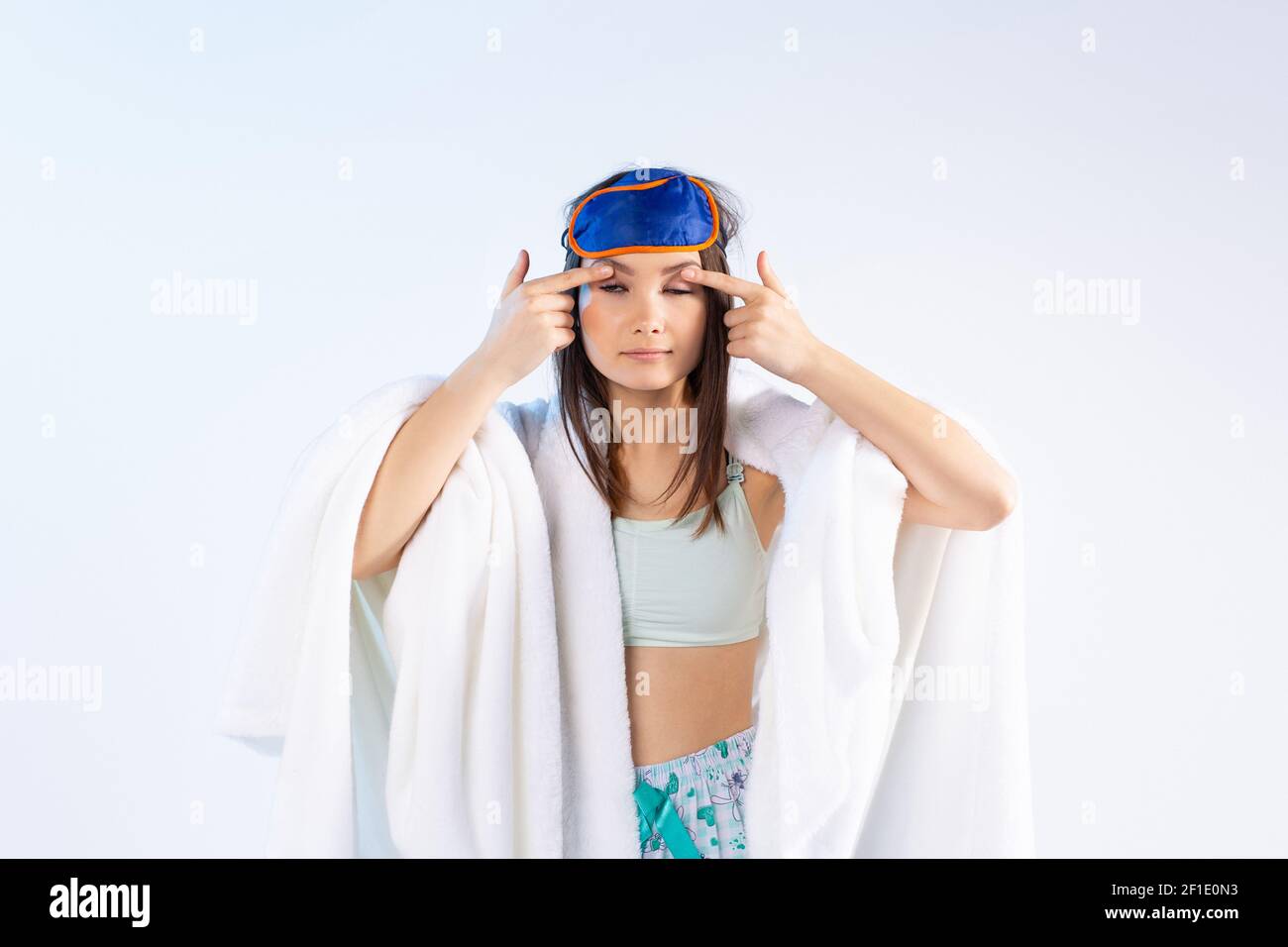 A sleepy girl in a mijama and with a fluffy blanket on her shoulders ...