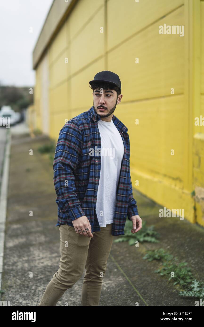A stylish young European male wearing a snapback hat posing on ...