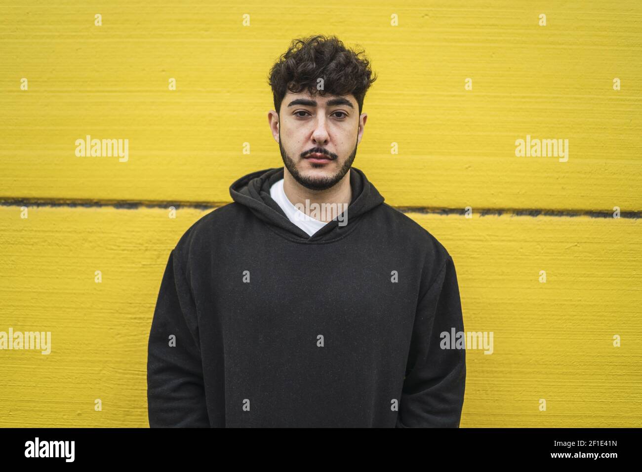 A young European male with a serious face expression on vibrant yellow ...