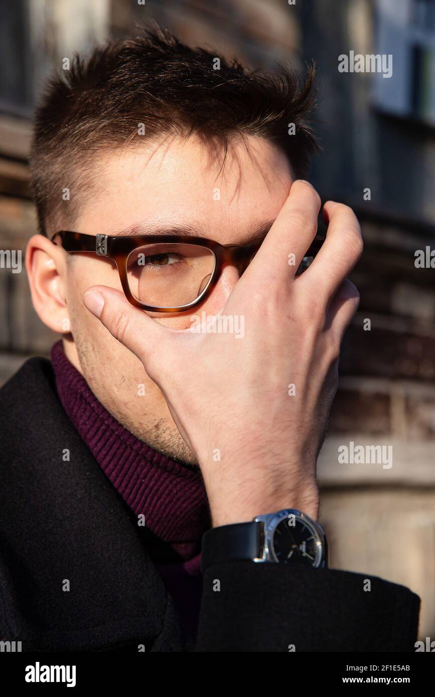 White european young man portrait outside covered his face by hand ...