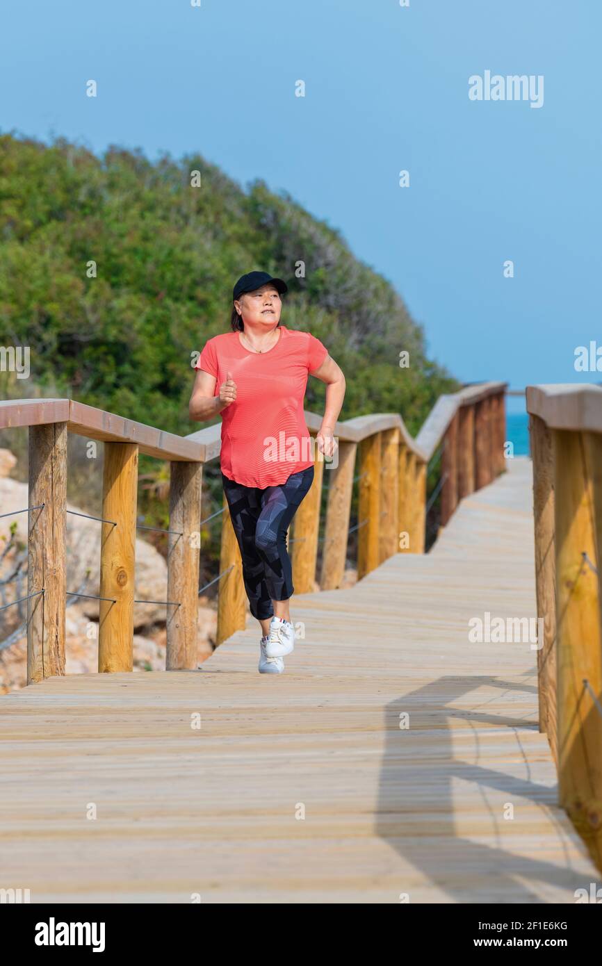 Mature woman running and looking very tired Stock Photo - Alamy