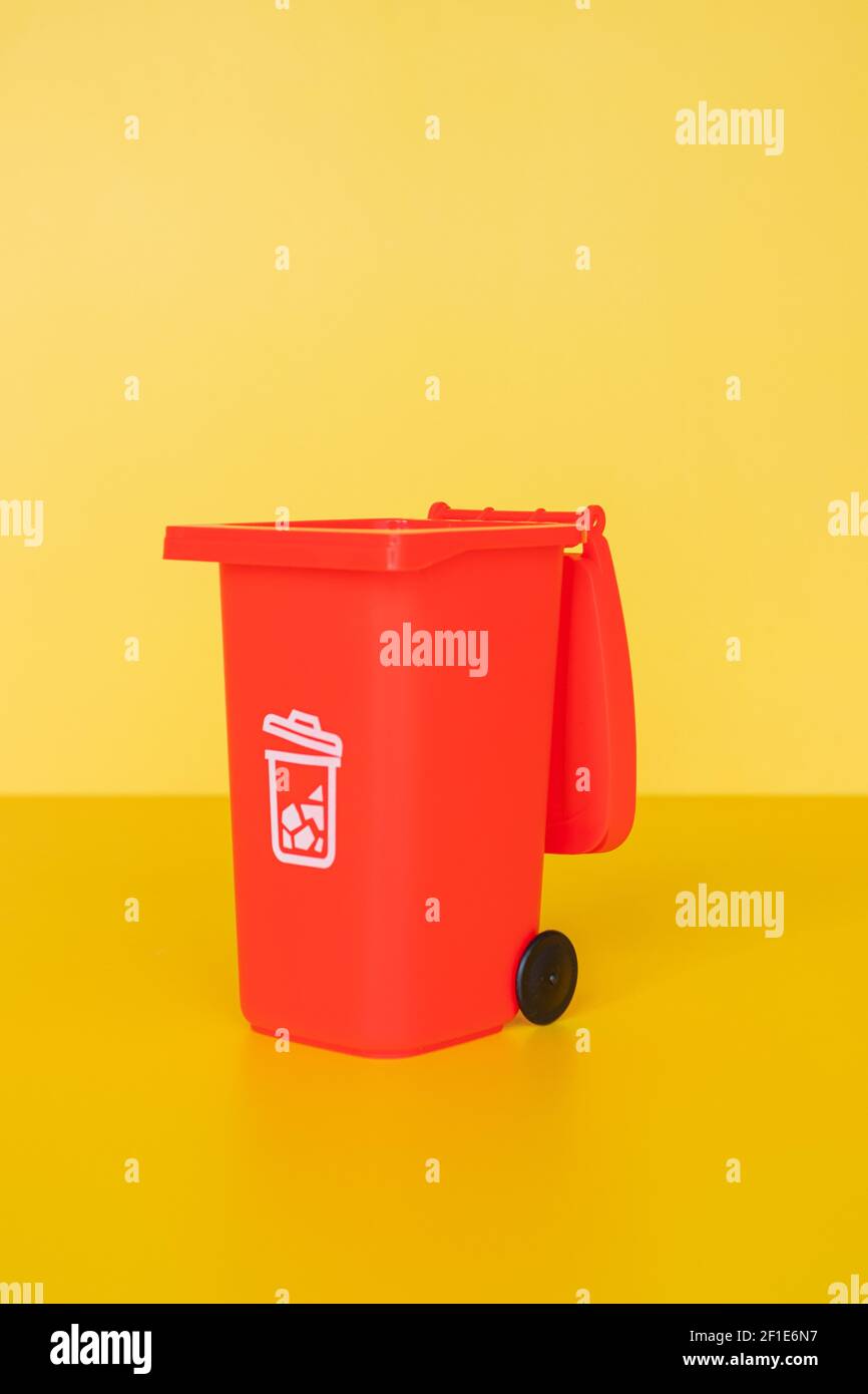 Red garbage container on yellow background Stock Photo - Alamy