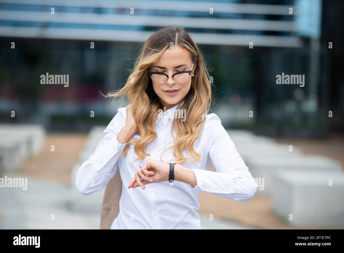Confident young female manager checking the time on her watch outdoor ...