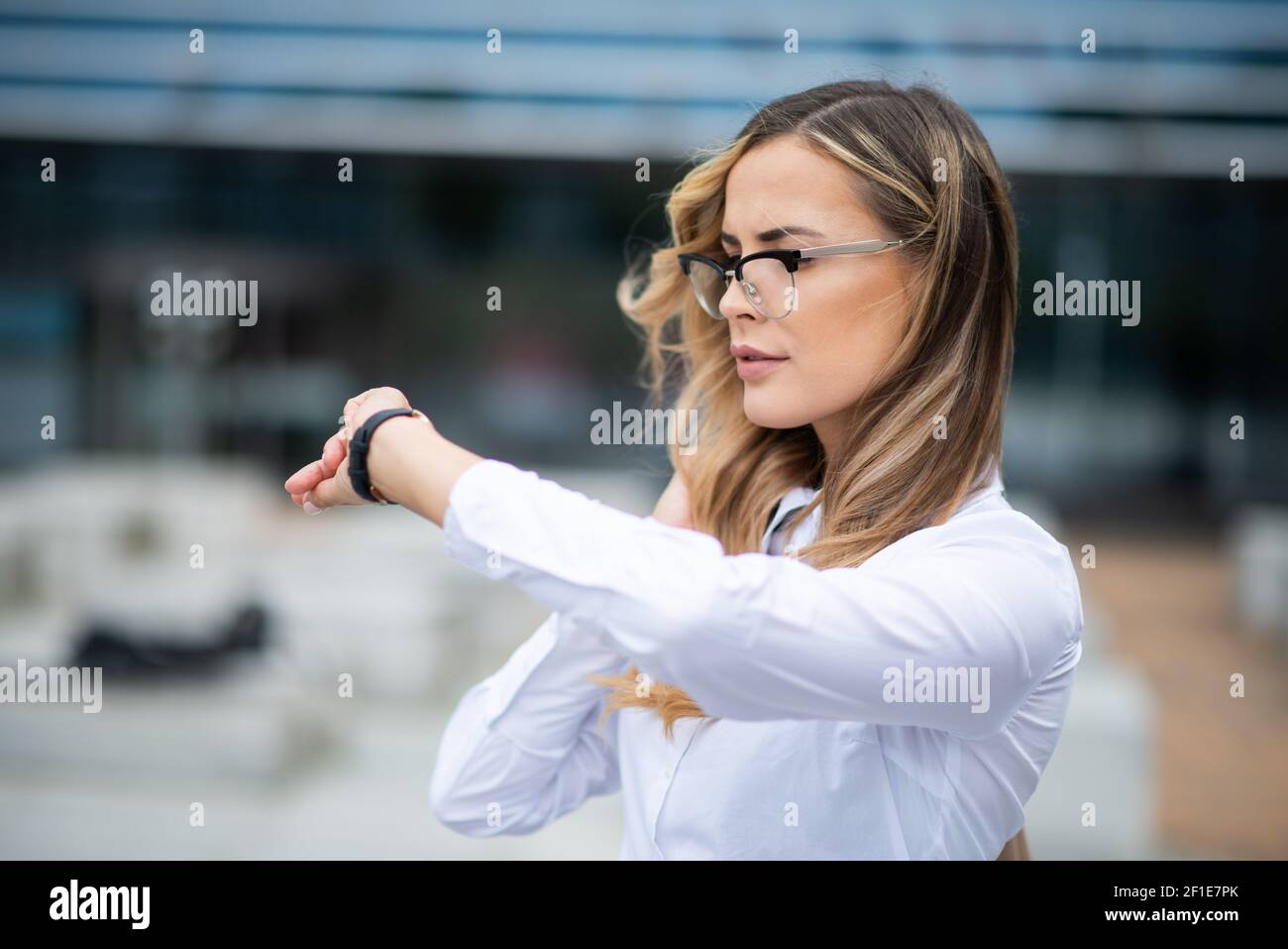 Confident young female manager checking the time on her watch outdoor ...
