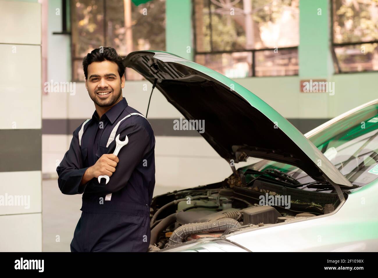 Portrait of happy mechanic in auto repair shop holding a spanner Stock ...