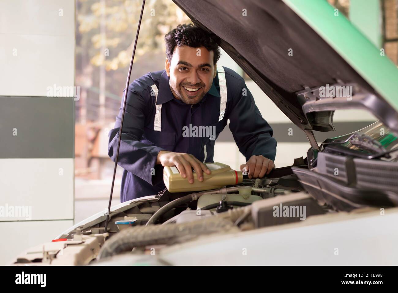 Mechanic refilling oil in a car at his workshop Stock Photo - Alamy