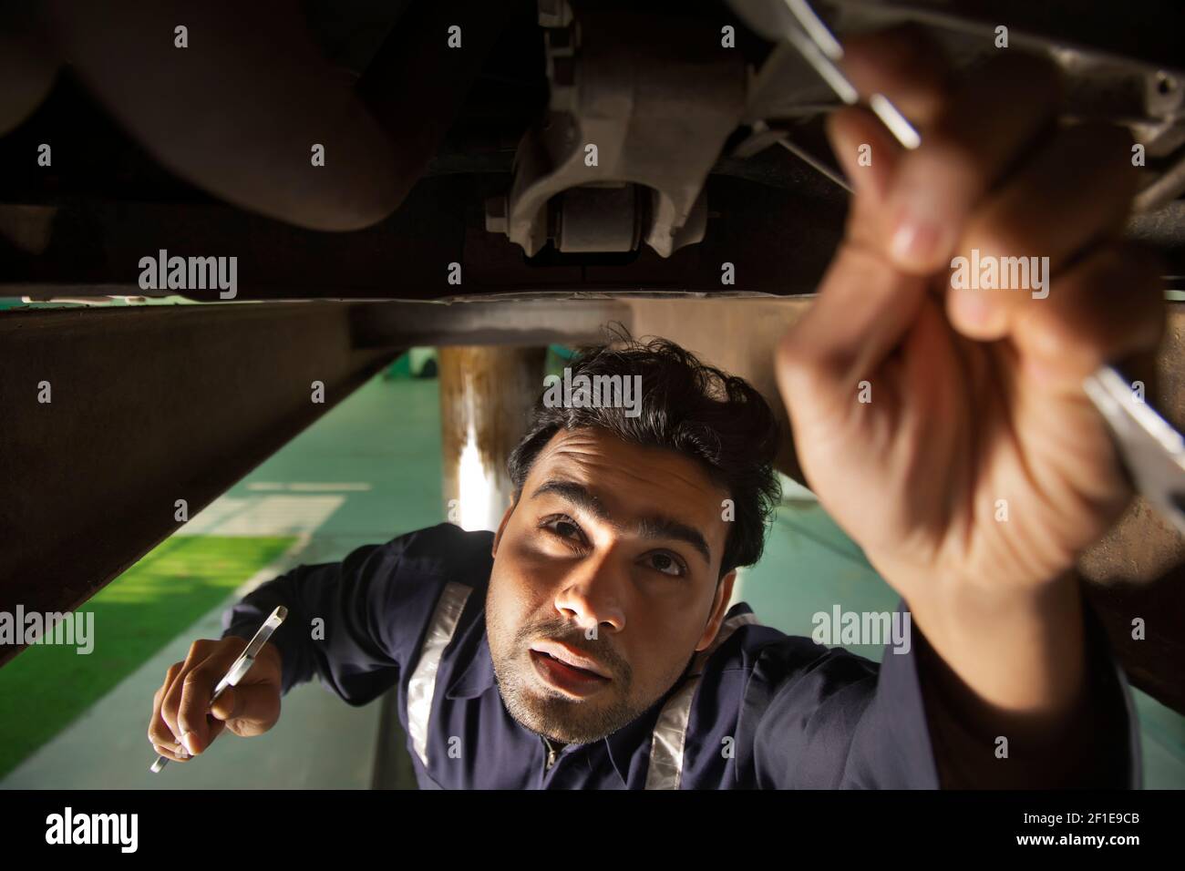 Car mechanic working under a vehicle at workshop Stock Photo - Alamy