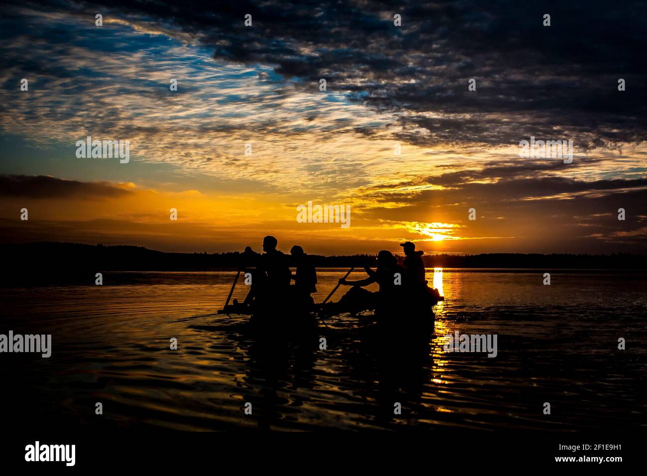 A group of people rowing in the sea with the sunset behind them Stock ...