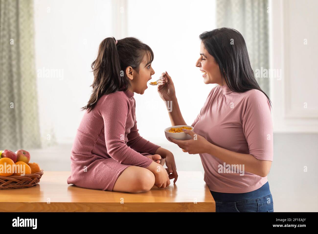 A DAUGHTER HAPPILY EATING CORNFLAKES GIVEN BY MOTHER Stock Photo - Alamy