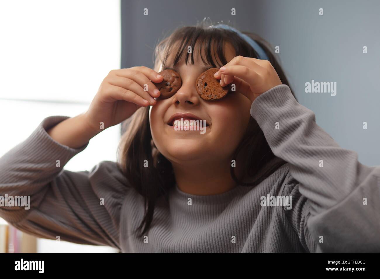 A HAPPY YOUNG GIRL PLACING BISCUITS ON EYES AND PLAYING Stock Photo - Alamy