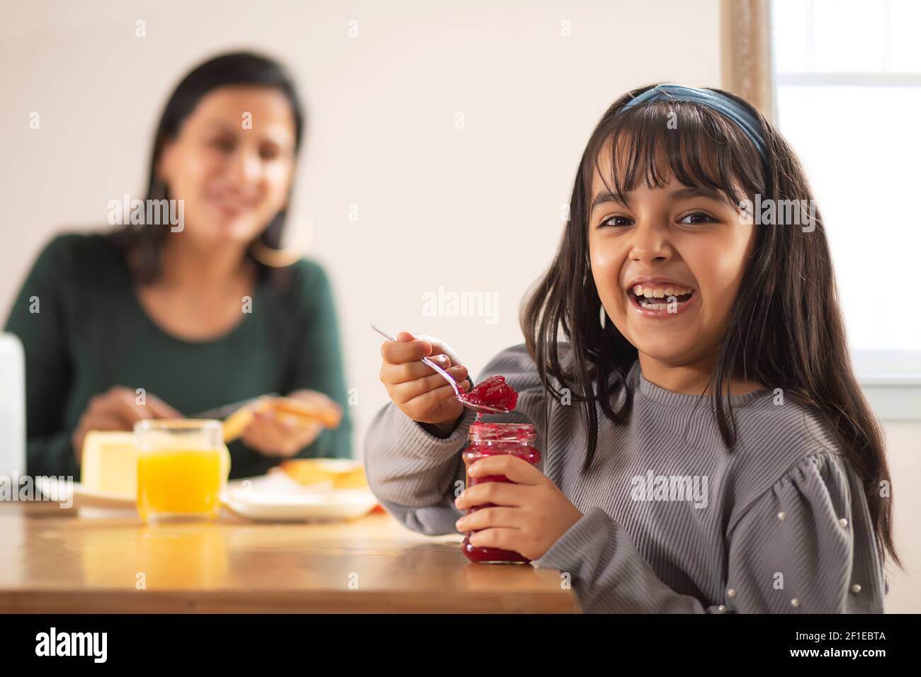 A CHEERFUL GIRL LOOKING AT CAMERA WHILE EATING JAM Stock Photo - Alamy