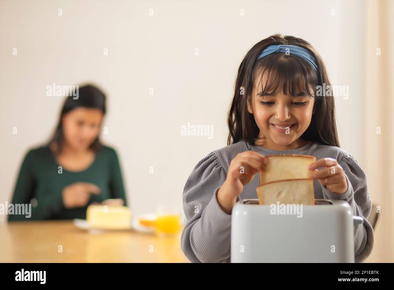 A HAPPY YOUNG GIRL PUTTING BREAD INSIDE AN ELECTRIC TOASTER Stock Photo ...