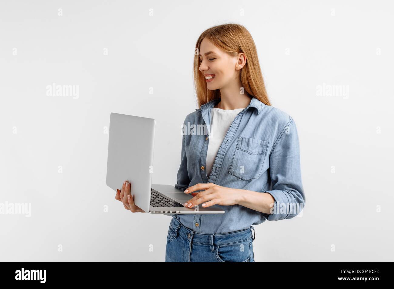 Image of a cheerful young woman using a laptop computer, on an isolated ...