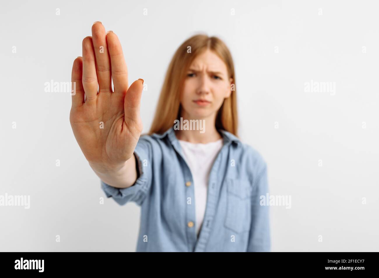 Portrait of serious young woman standing with outstretched hand showing ...